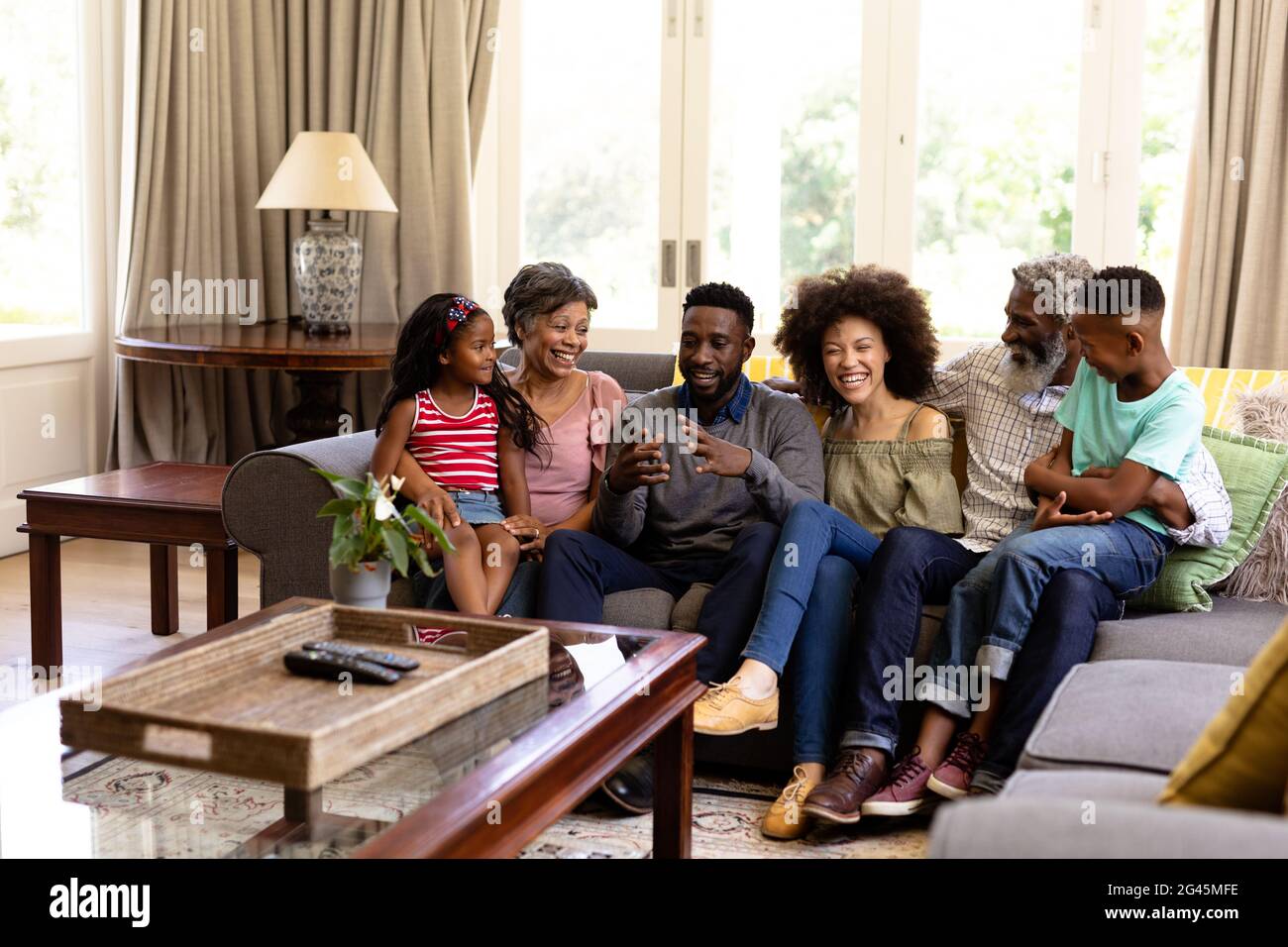Multi-generation mixed race family spending time together sitting on a ...