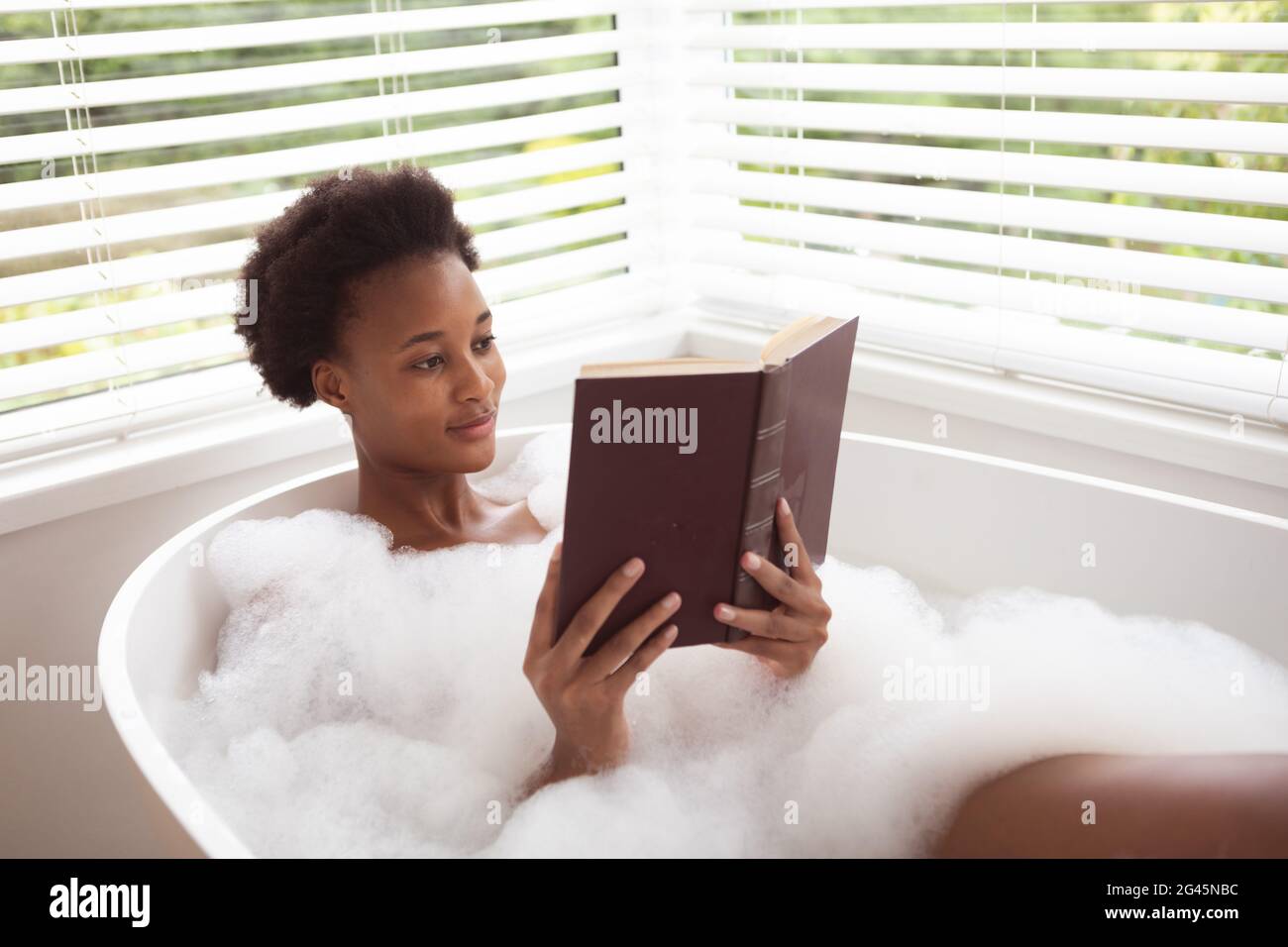 Woman reading book in a bathtub Stock Photo - Alamy