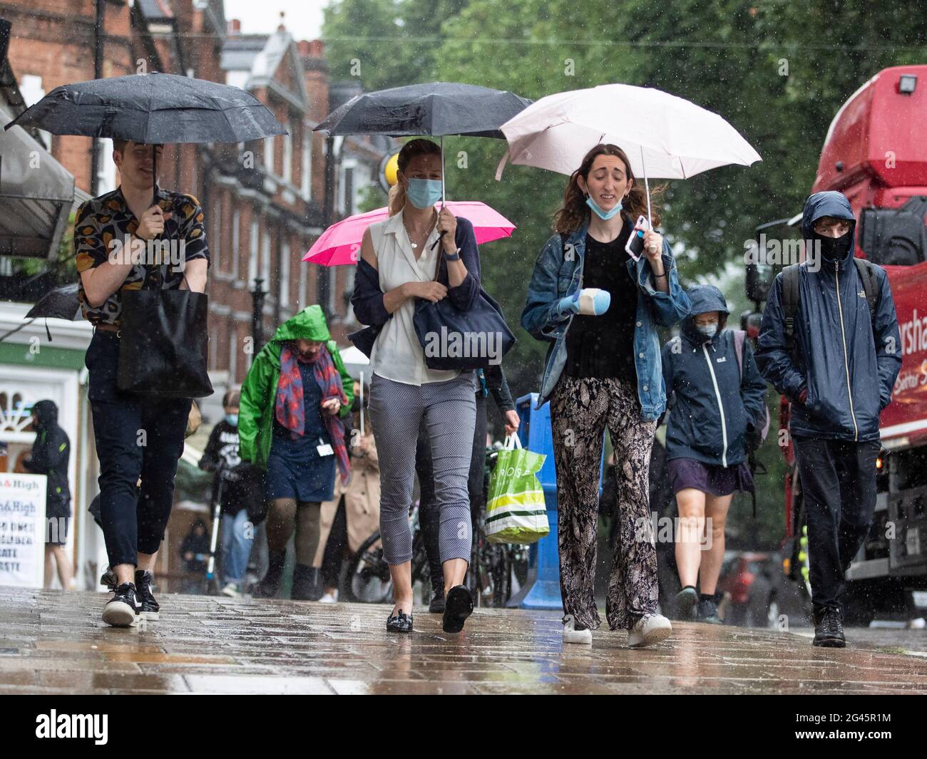 People walk through torrential rain in Hampstead, North London as the ...