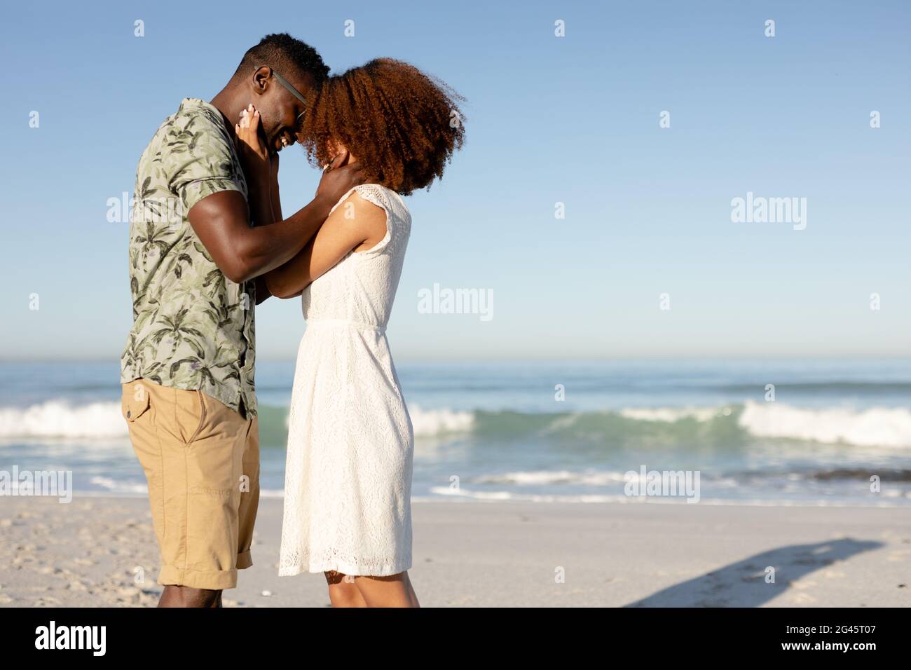 Mixed race couple holding cheeks on the beach Stock Photo - Alamy