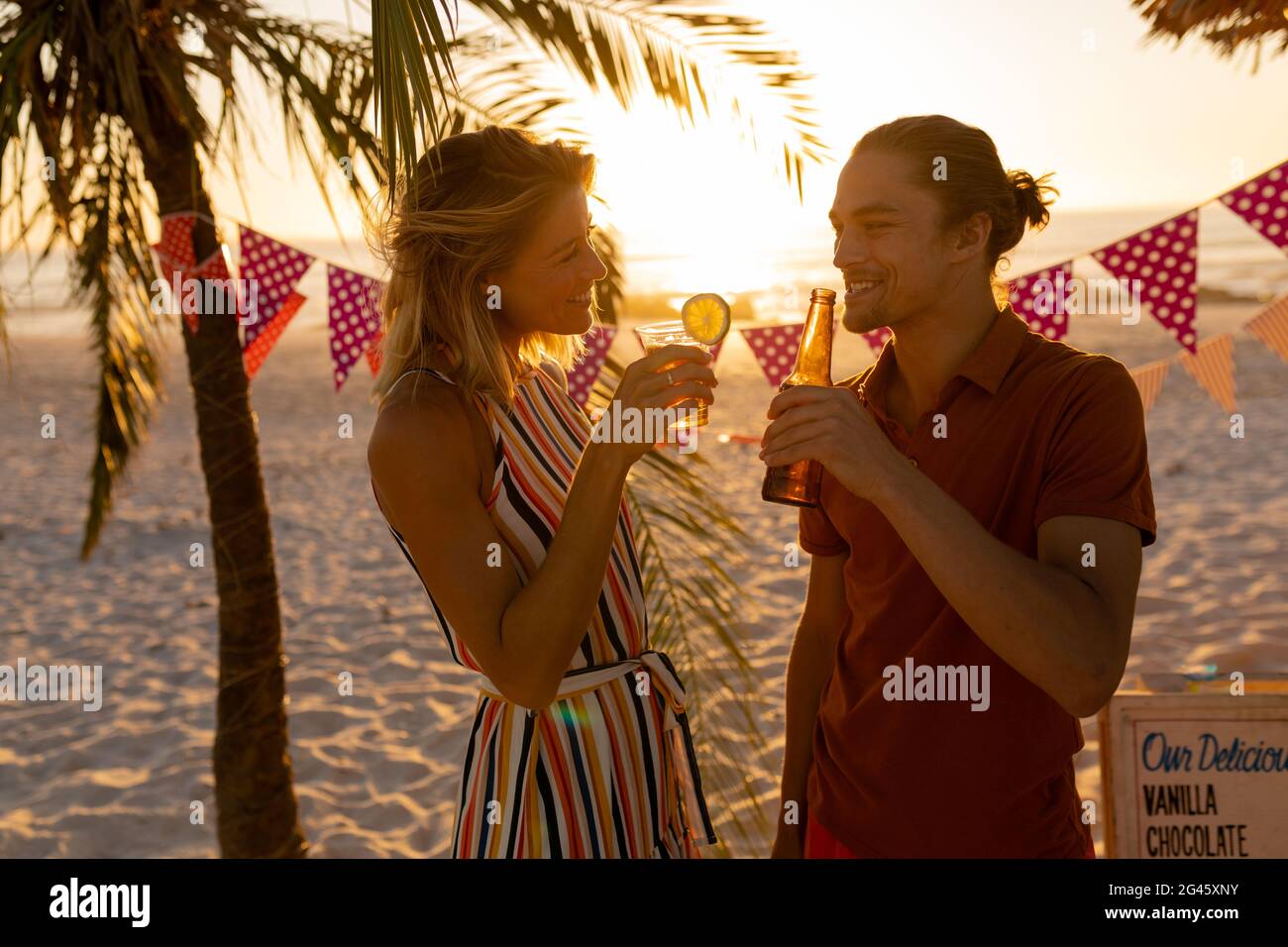 Caucasian couple smiling and drinking alcohol on beach Stock Photo - Alamy