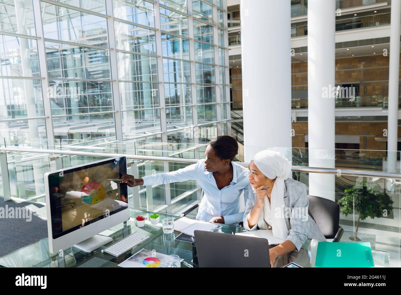 Females executives discussing over computer at desk Stock Photo - Alamy