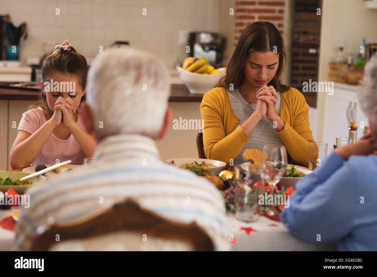 Multi generation caucasian family sitting at table for christmas dinner ...