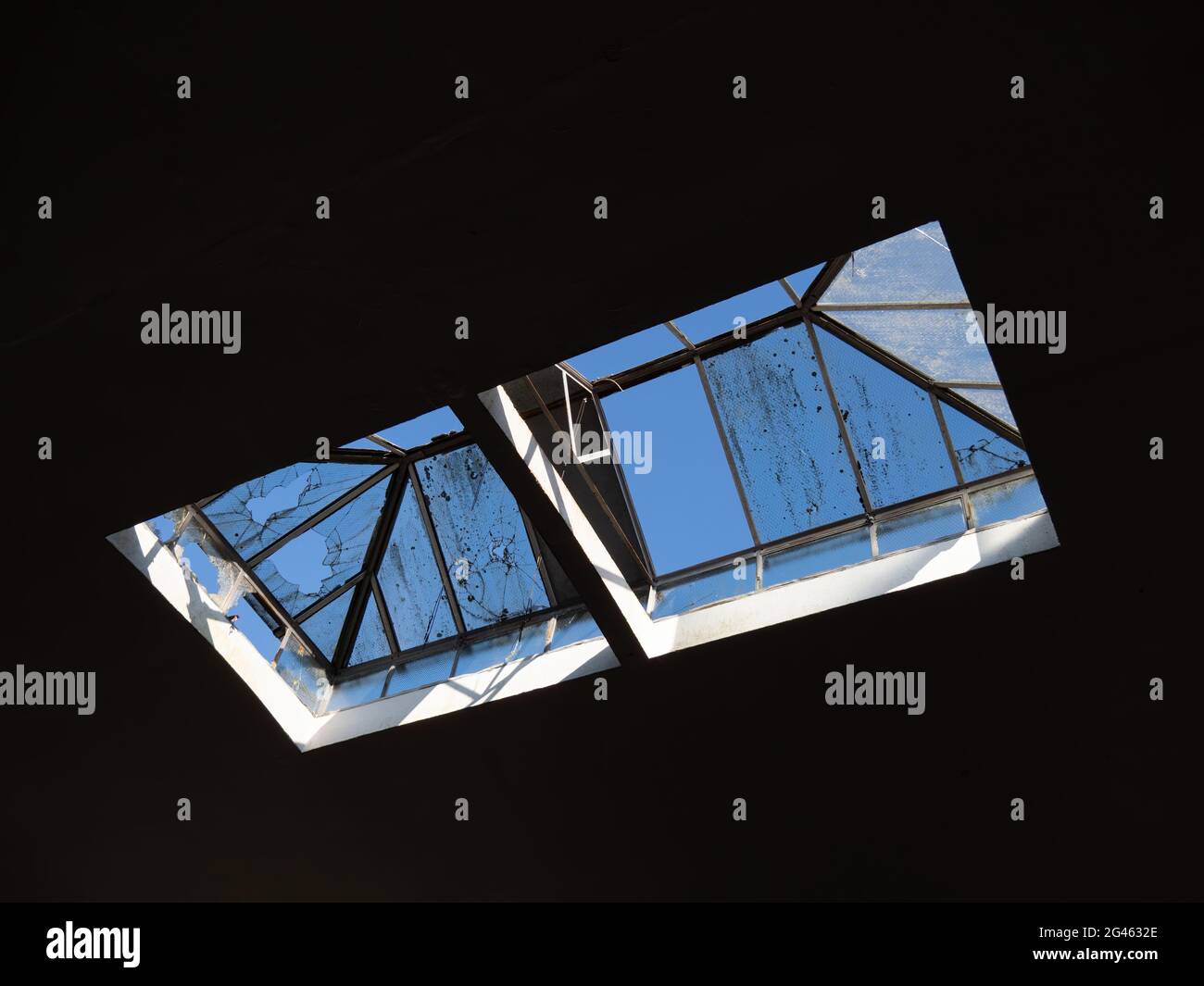 Old broken skylight in abandoned factory. Sunshine blue sky beyond ...