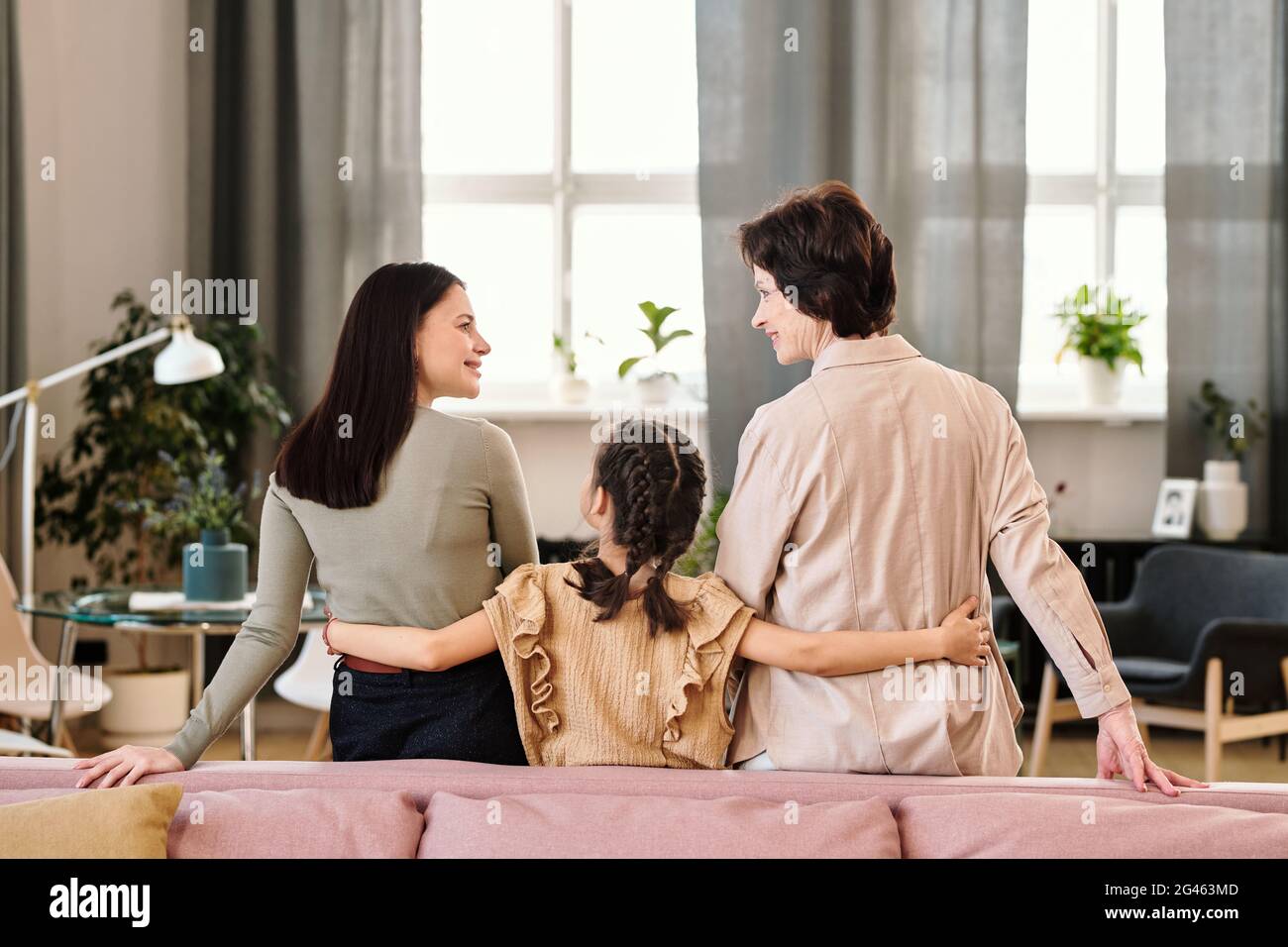Back view of three happy females standing by couch Stock Photo - Alamy