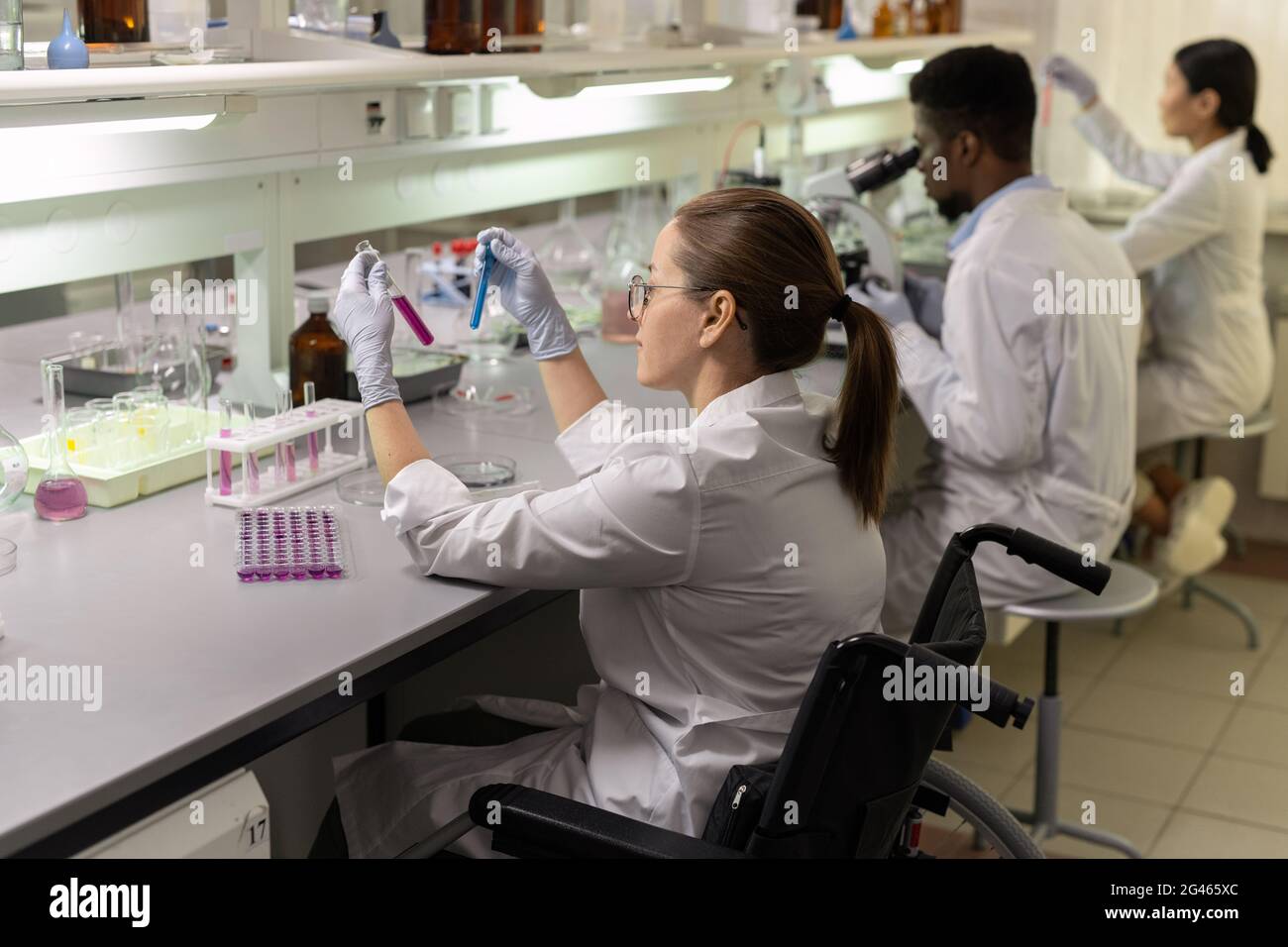 Group of intercultural lab workers sitting in row during scientific ...