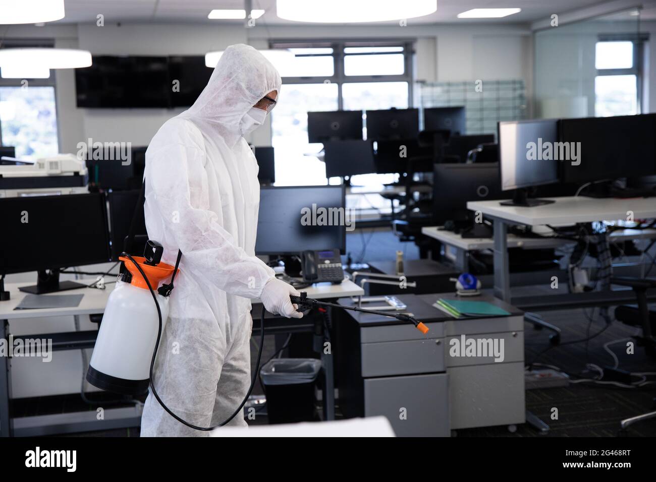 Health worker wearing protective clothes cleaning the office using ...
