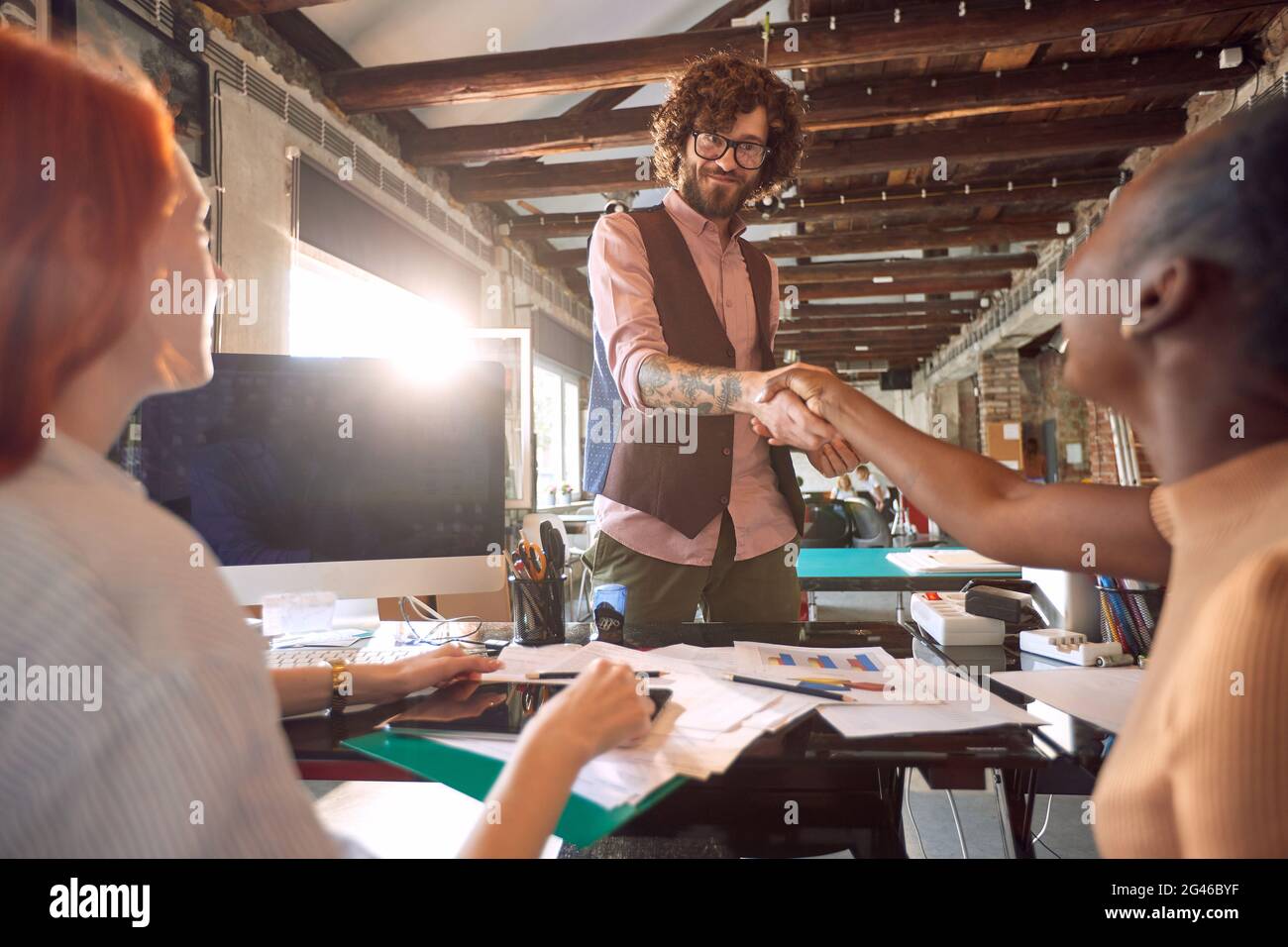 A young man in a pleasant atmosphere in the office congratulate his ...