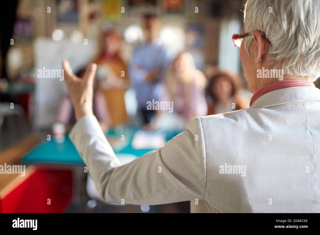 Elderly female boss talking to office staff during a meeting in a ...