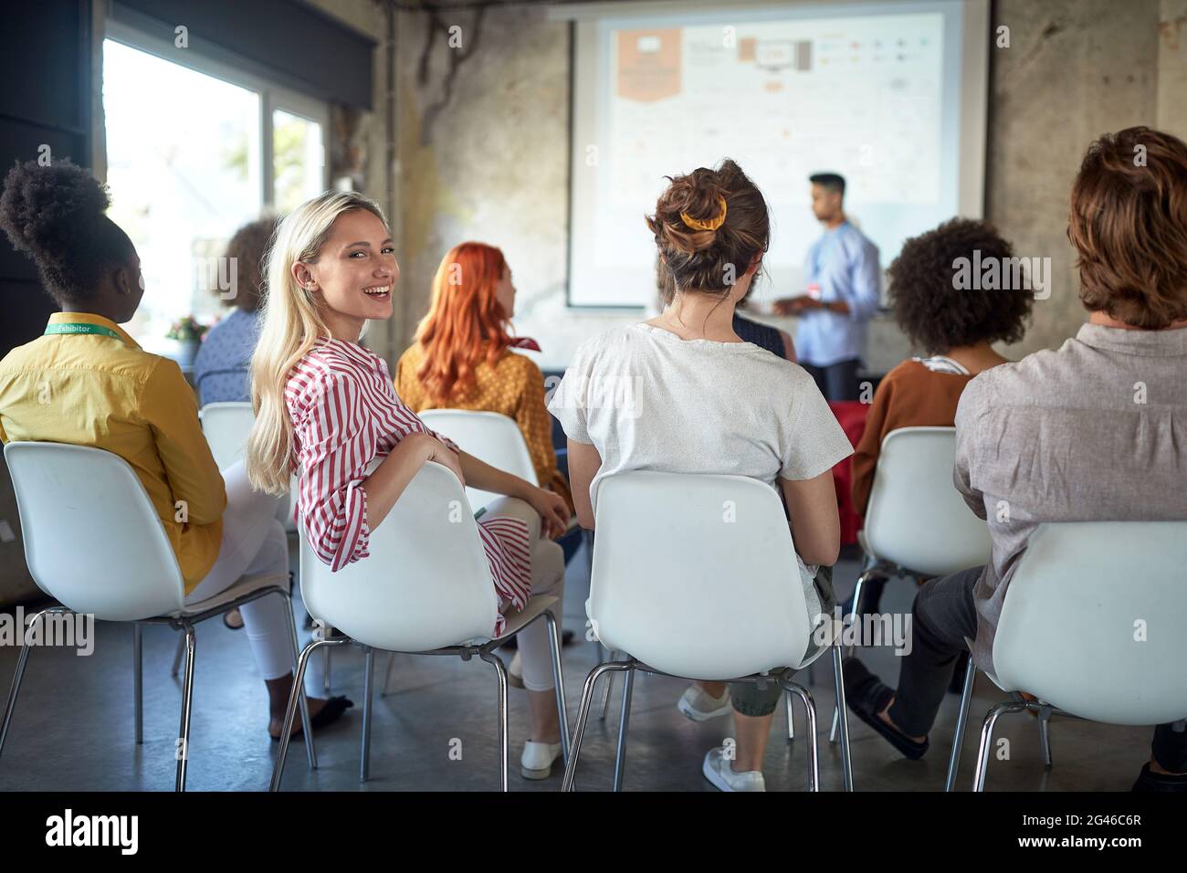 A young woman is posing for a photo while enjoying her colleague presentation in a pleasant ...