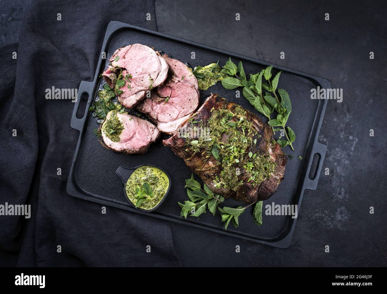Traditional English barbecue lamb roast sliced with mint leaf and sauce ...