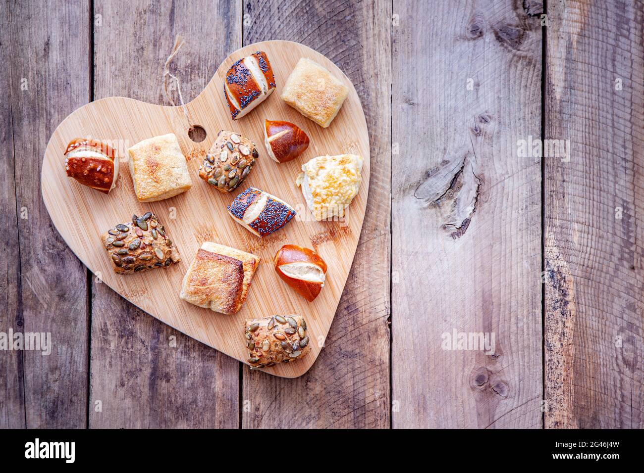 Many small buns lie in heart form on a rustic background Stock Photo ...