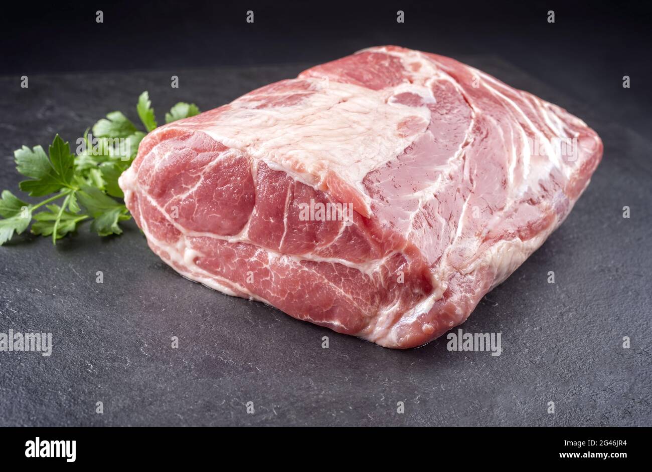 Traditional raw corned pot pork roast with parsley offered as close-up ...