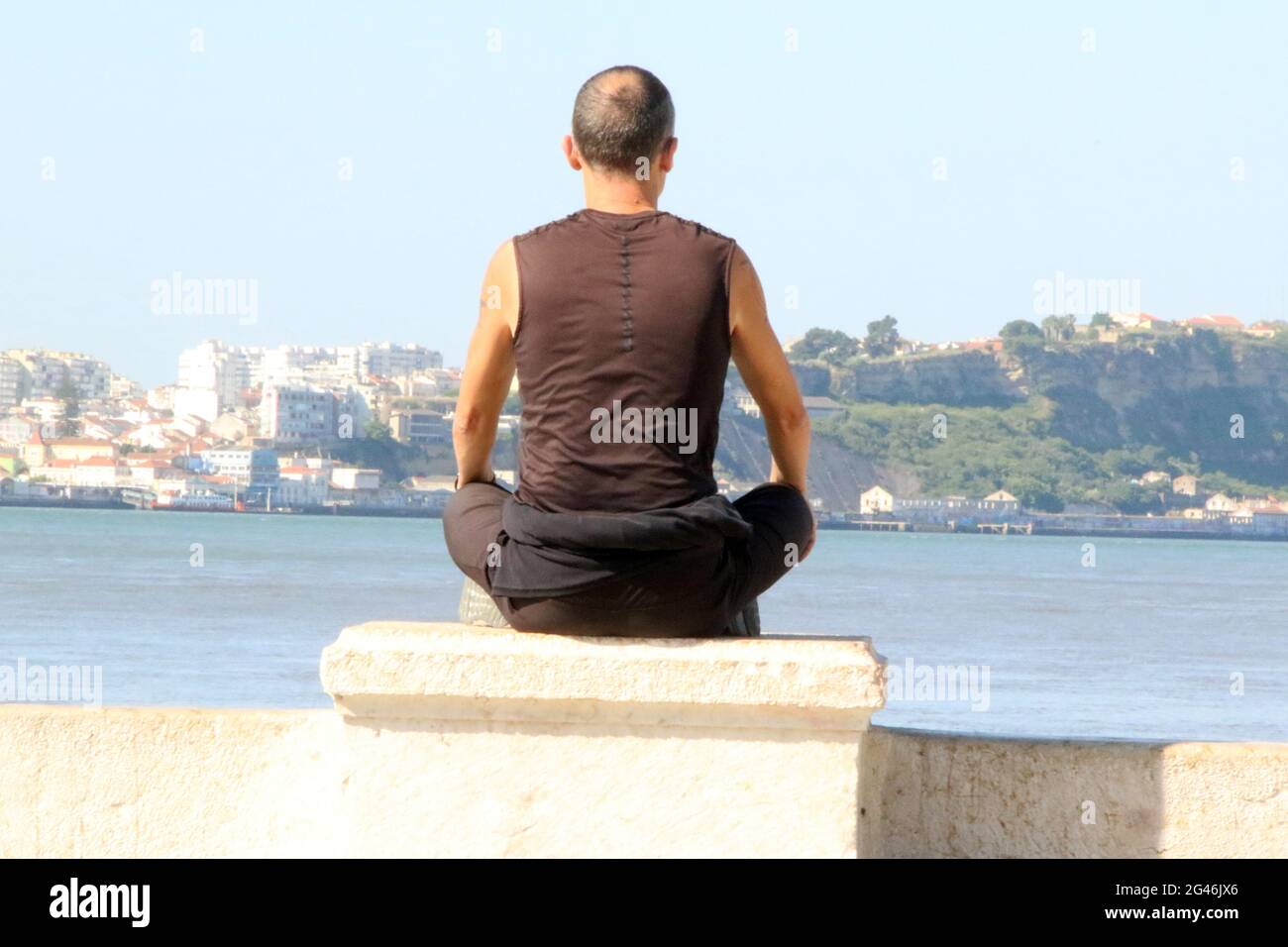 Closeup shot of a male meditating on a wall of a beach Stock Photo - Alamy