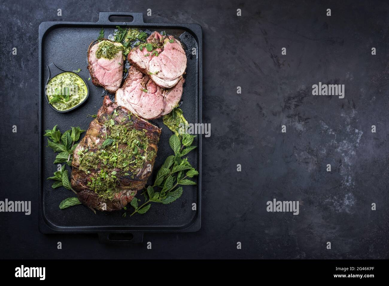 Traditional English barbecue lamb roast sliced with mint leaf and sauce ...