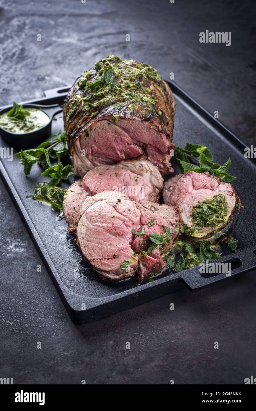 Traditional English barbecue lamb roast sliced with mint leaf and sauce ...