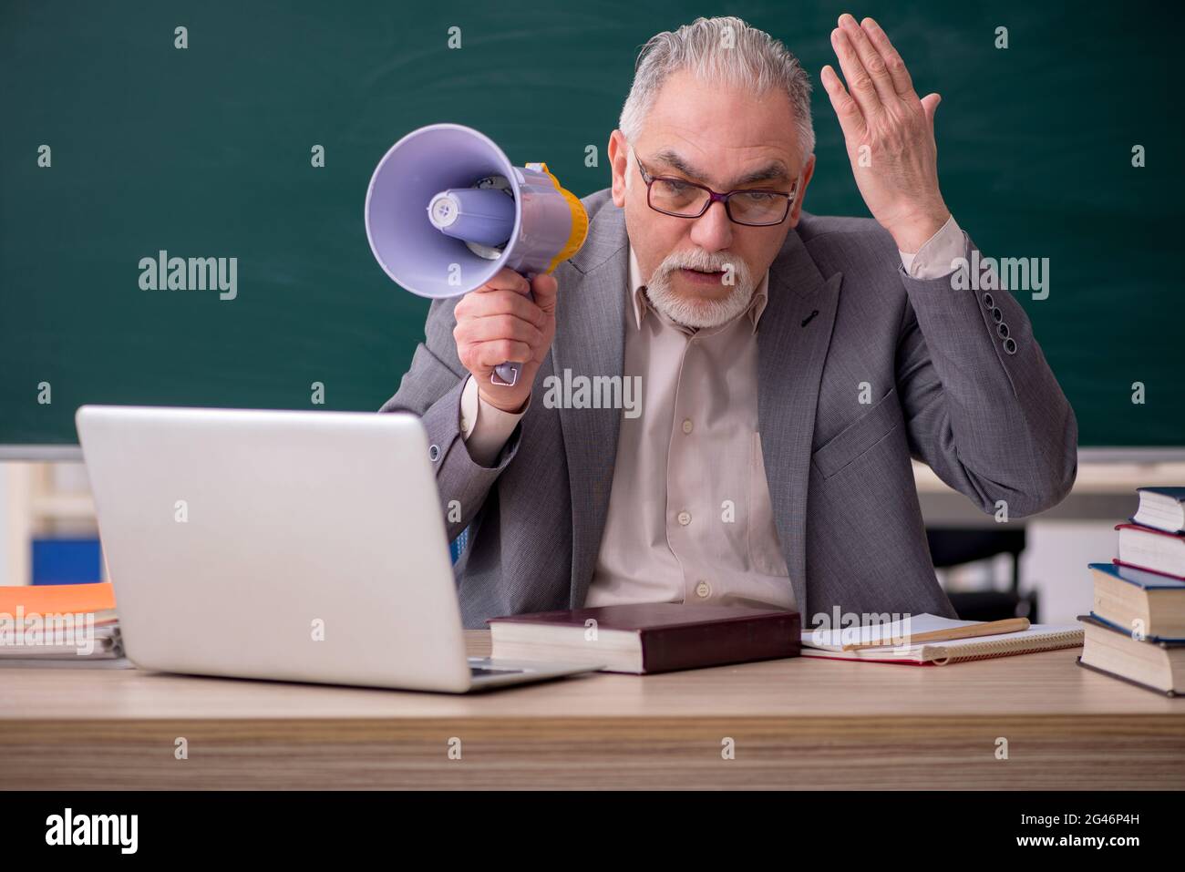 Old teacher holding megaphone in front of blackboard Stock Photo - Alamy