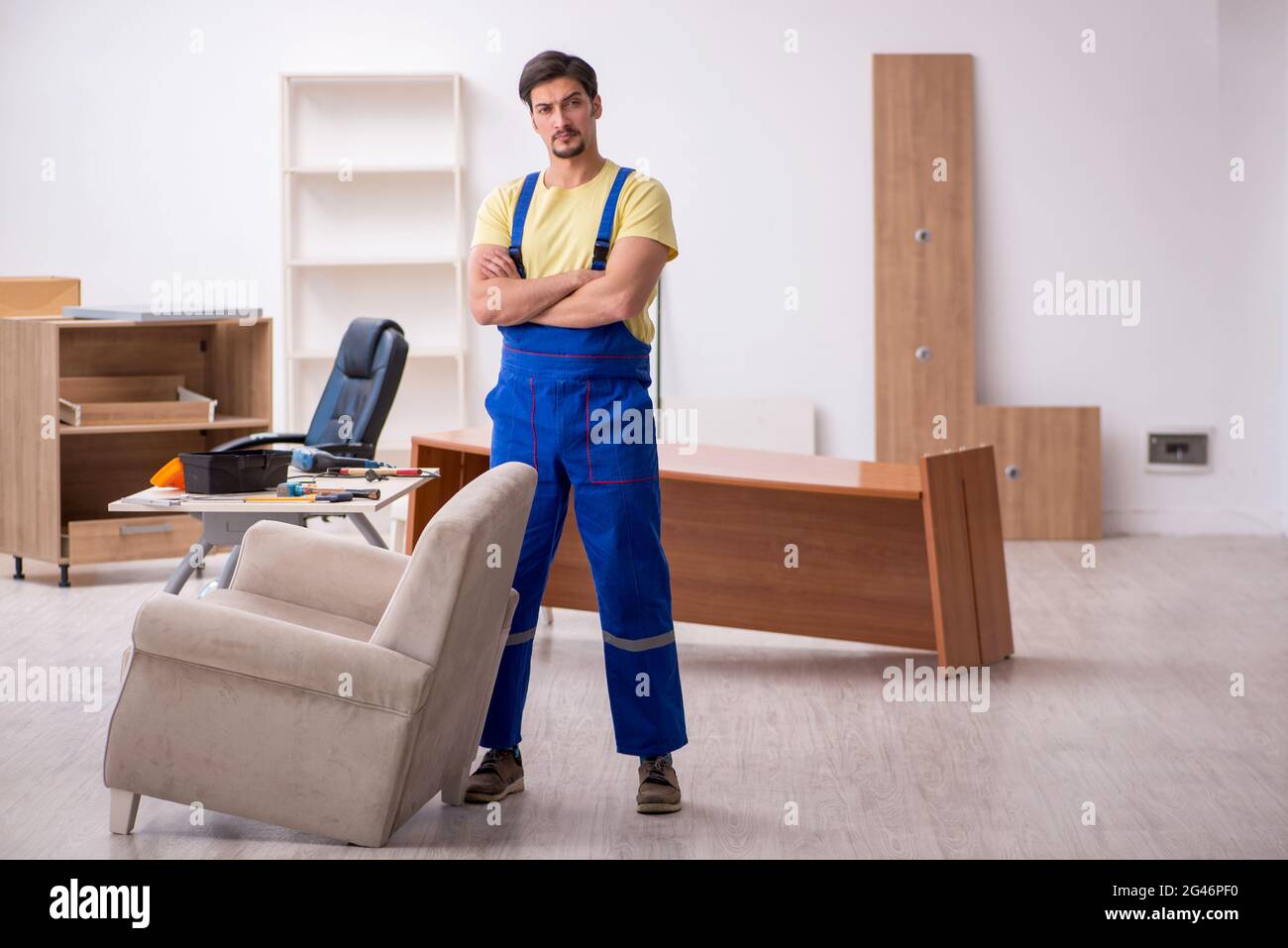 Young carpenter repairing arm-chair in the office Stock Photo - Alamy