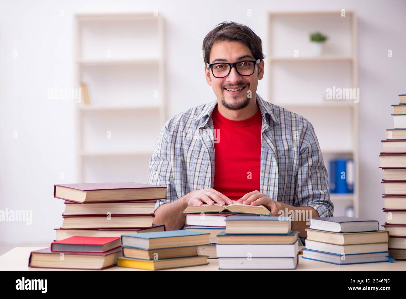 Young student and too many books in the classroom Stock Photo - Alamy