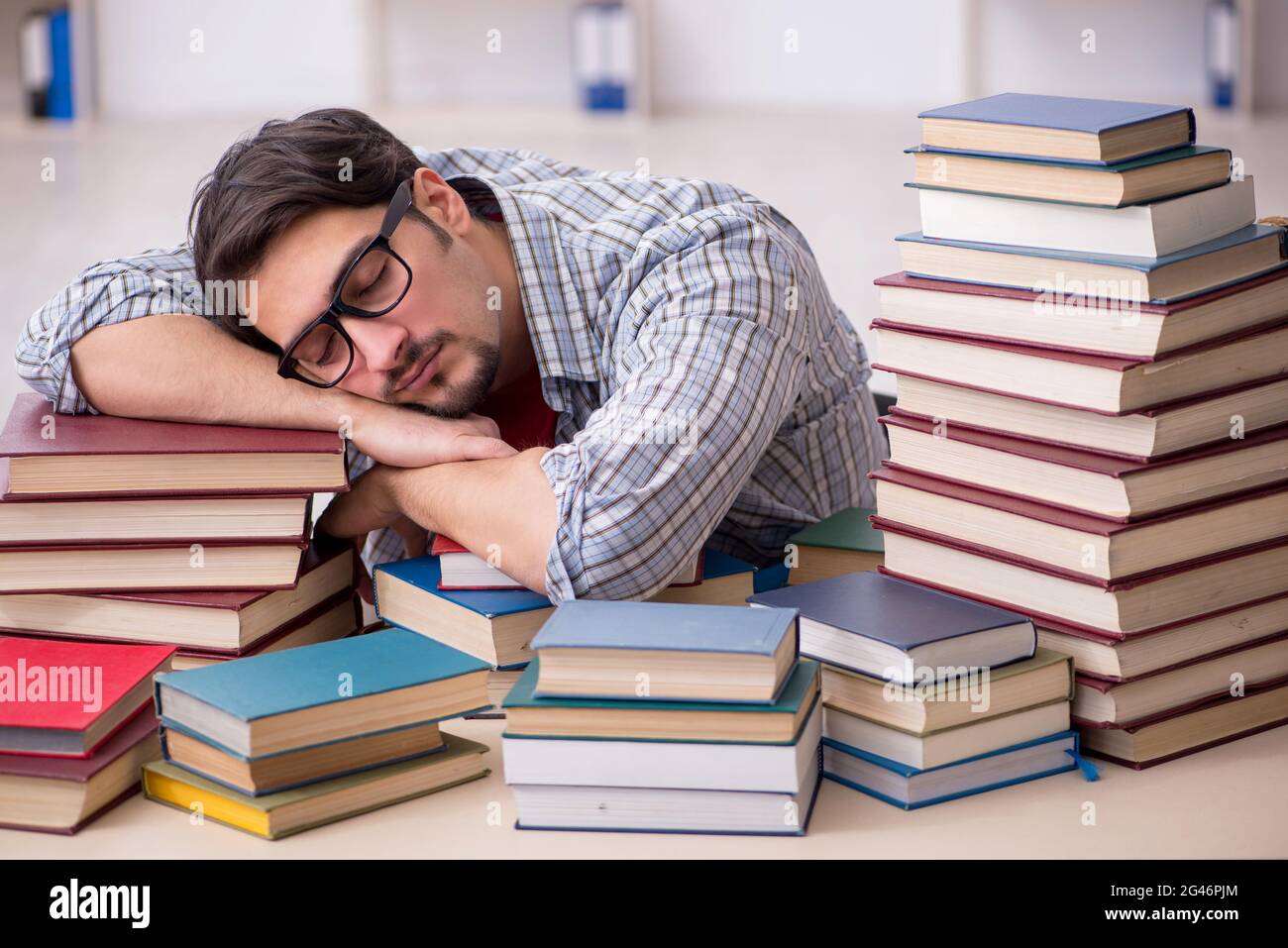 Young student and too many books in the classroom Stock Photo - Alamy