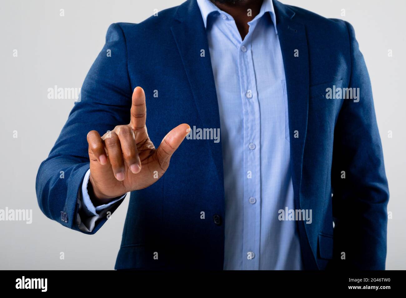 Mid section of businessman touching invisible screen against grey ...