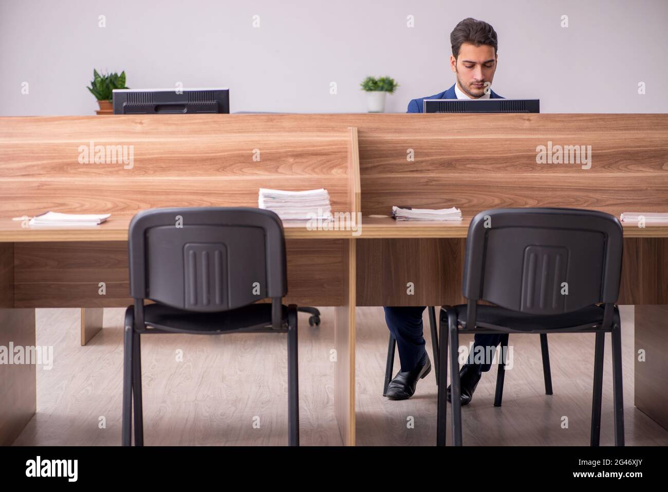 Young male employee sitting at workplace Stock Photo - Alamy