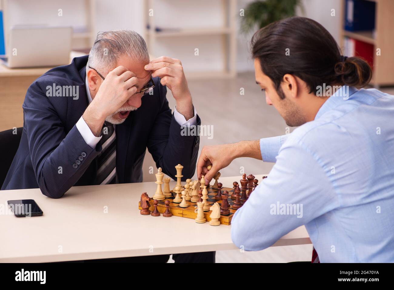 Two male employees playing chess at workplace Stock Photo - Alamy