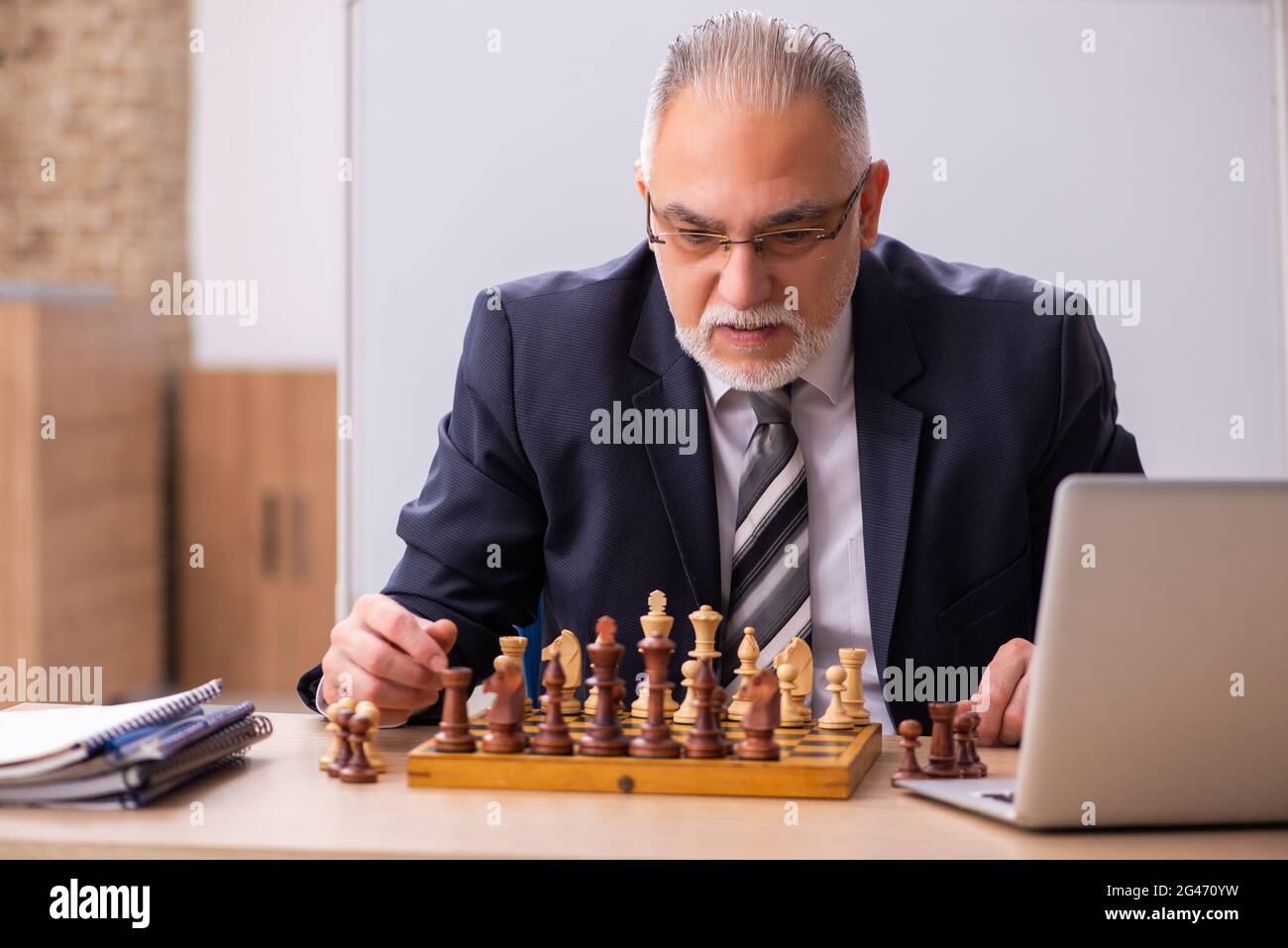 Old businessman employee playing chess at workplace Stock Photo - Alamy