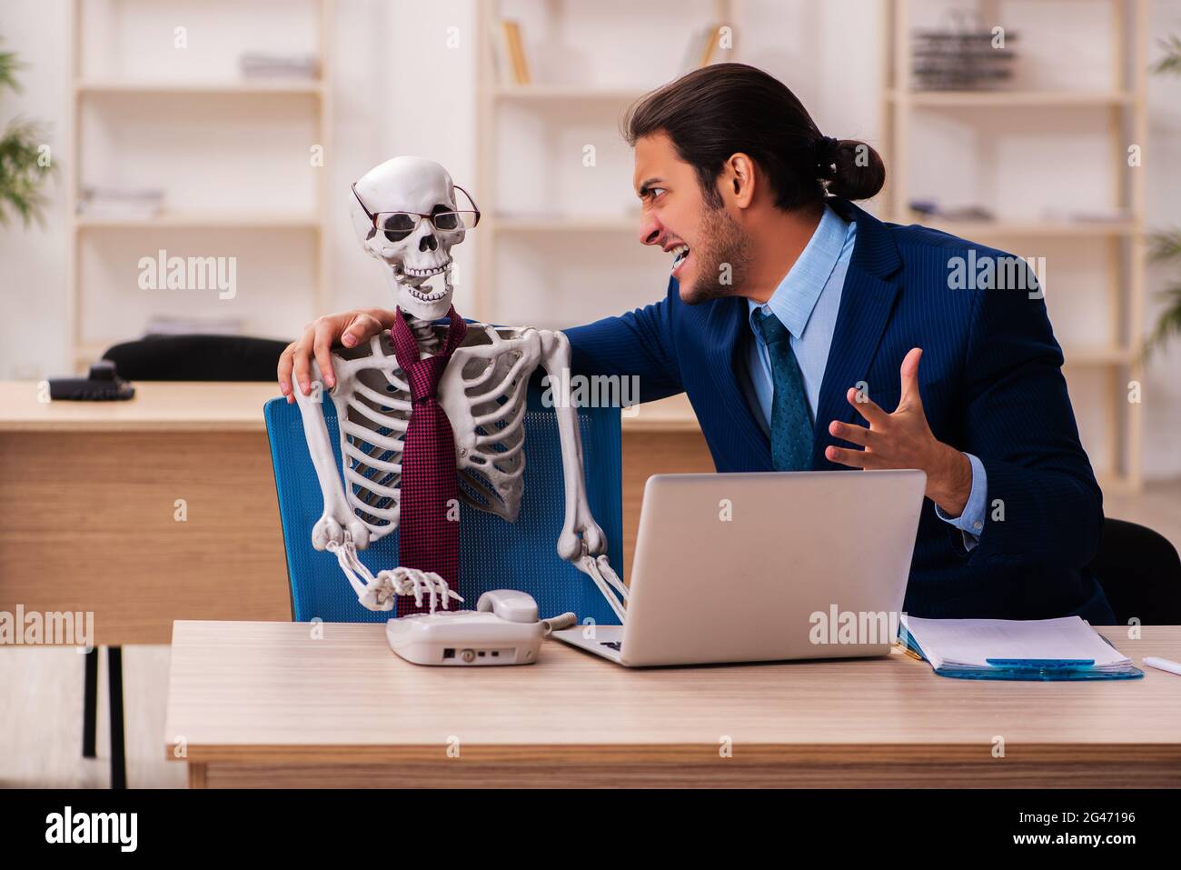 Dead employee working in the office in funny concept Stock Photo - Alamy