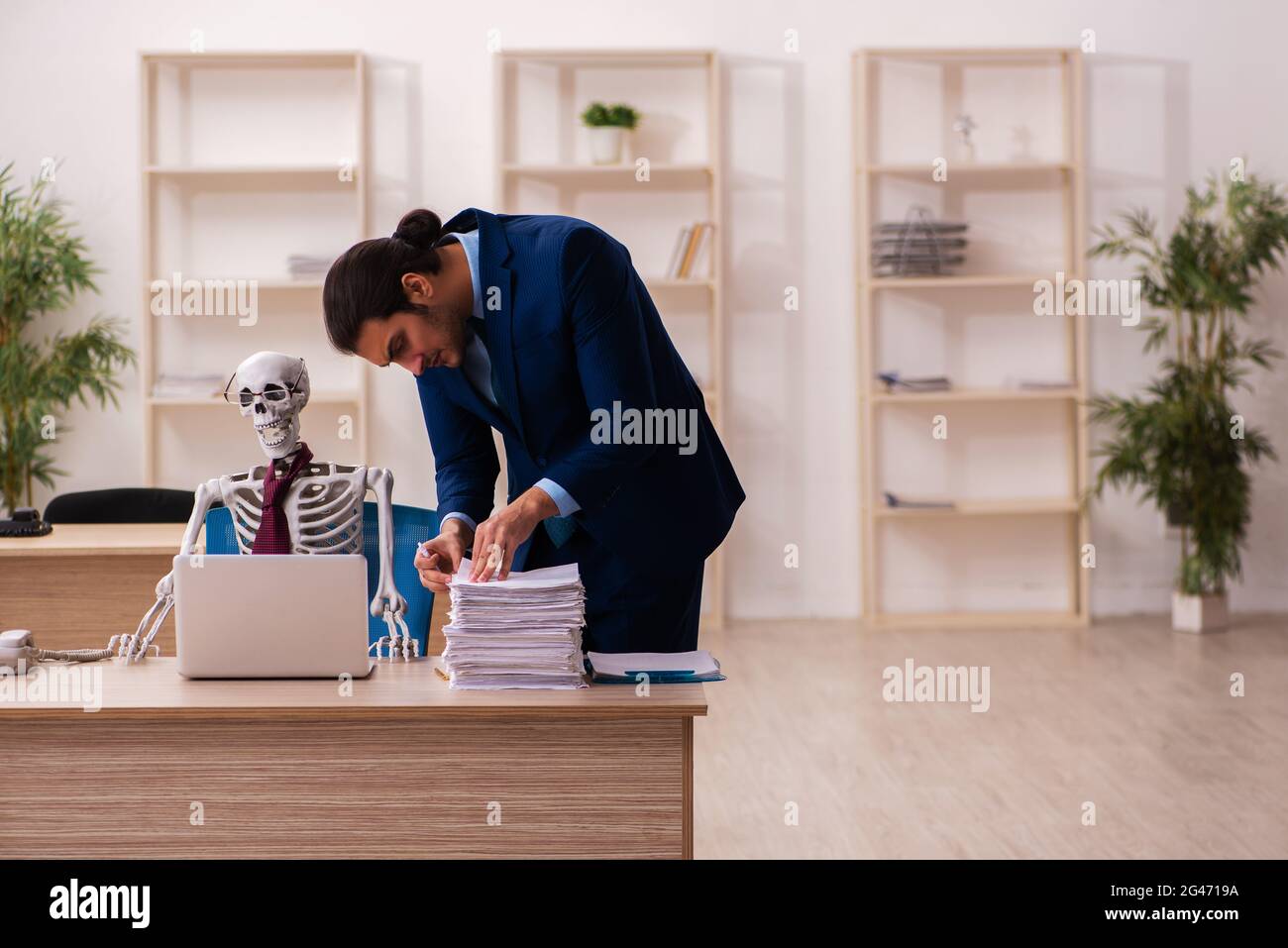 Dead employee working in the office in funny concept Stock Photo - Alamy