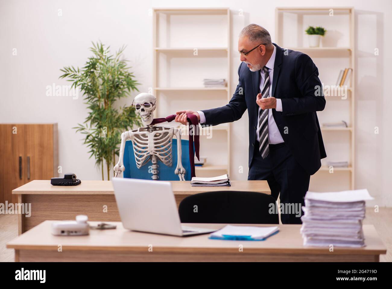 Dead employee working in the office in funny concept Stock Photo - Alamy