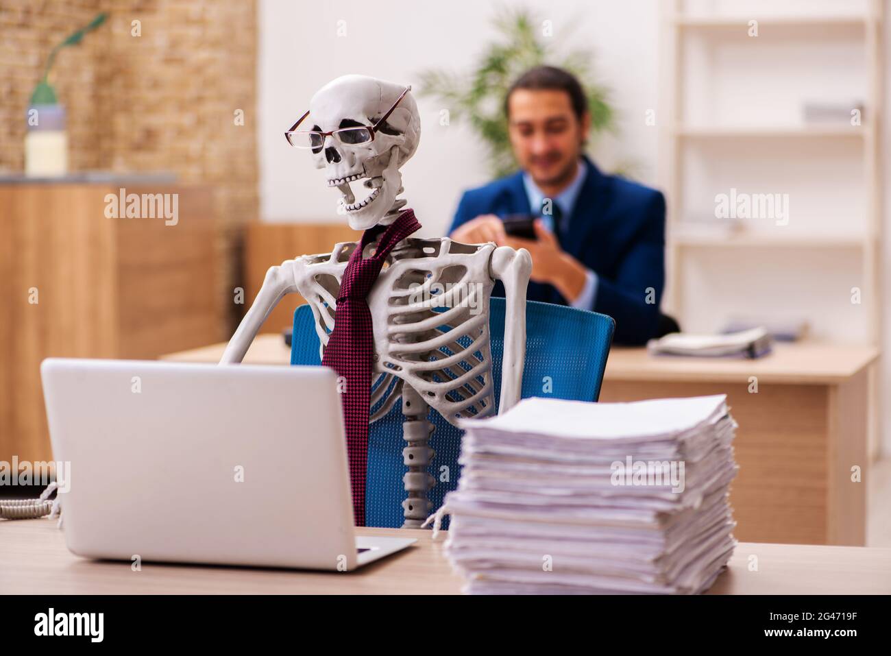 Dead employee working in the office in funny concept Stock Photo - Alamy