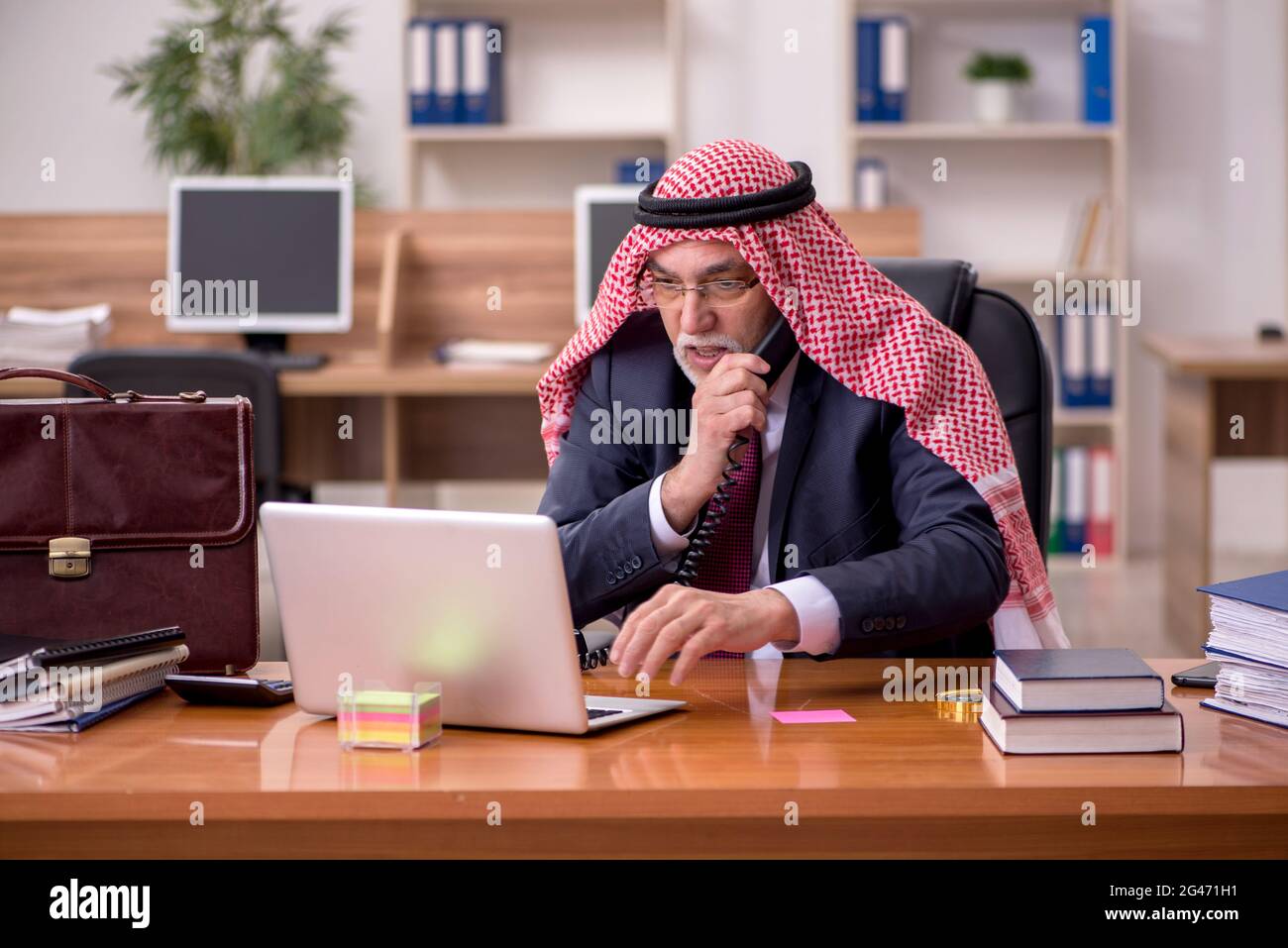 Old male arab employee sitting at workplace Stock Photo - Alamy