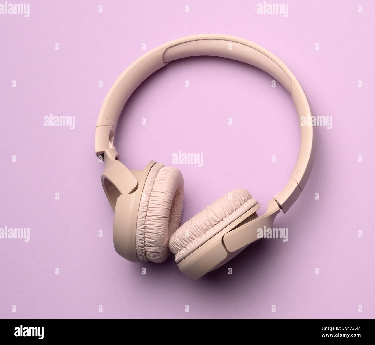 Beige wireless headphones on a purple background Stock Photo - Alamy