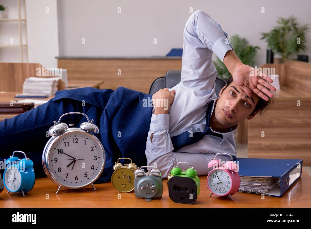 Young businessman sleeping in the office in time management concept ...