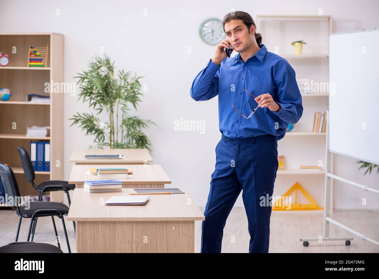 Young teacher holding smartphone during lesson Stock Photo - Alamy
