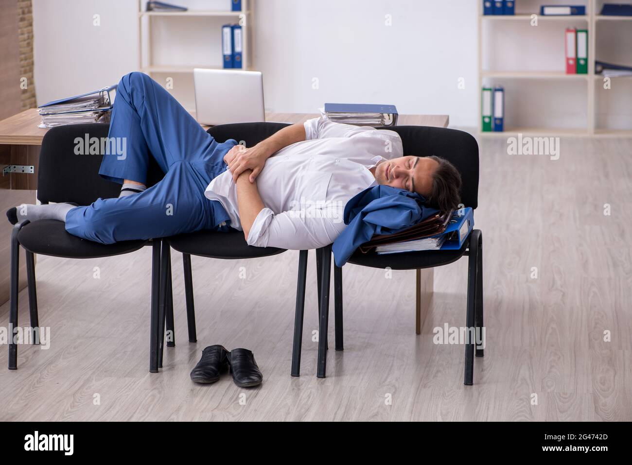 Young employee sleeping in the office on chairs Stock Photo - Alamy