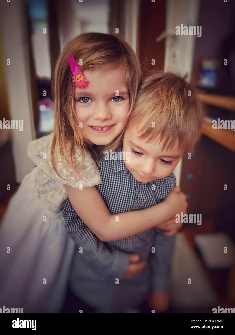 Shot of the Caucasian blonde kid holding her younger brother in her ...