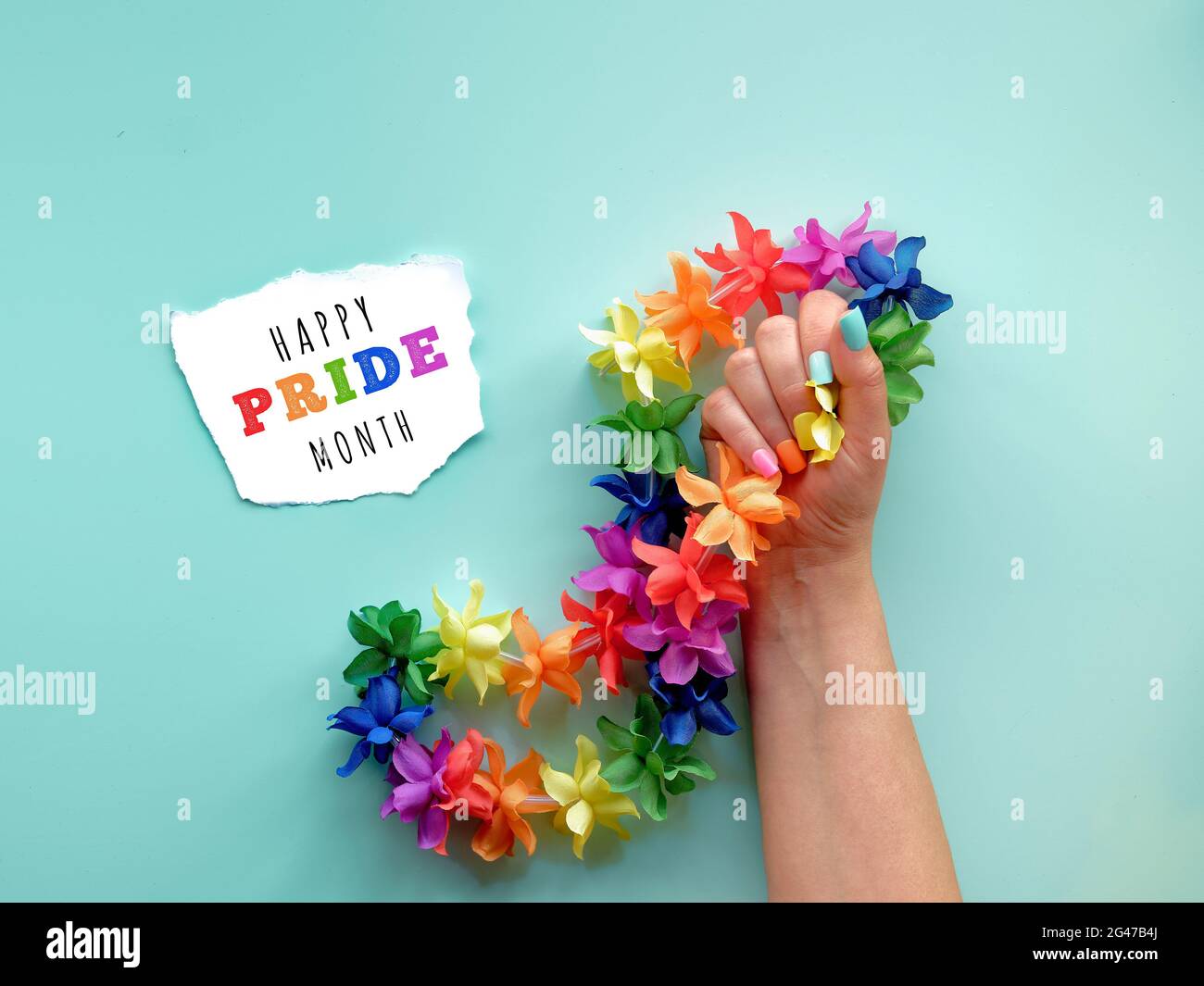 LGBTQ community pride month text on paper scrap. Hand with fake nails ...