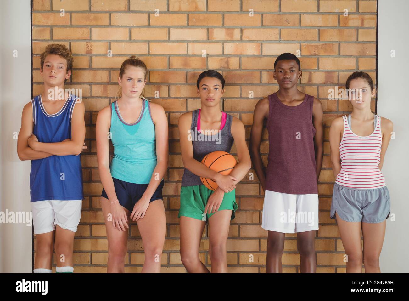 High school kids leaning against the wall in basketball court Stock ...