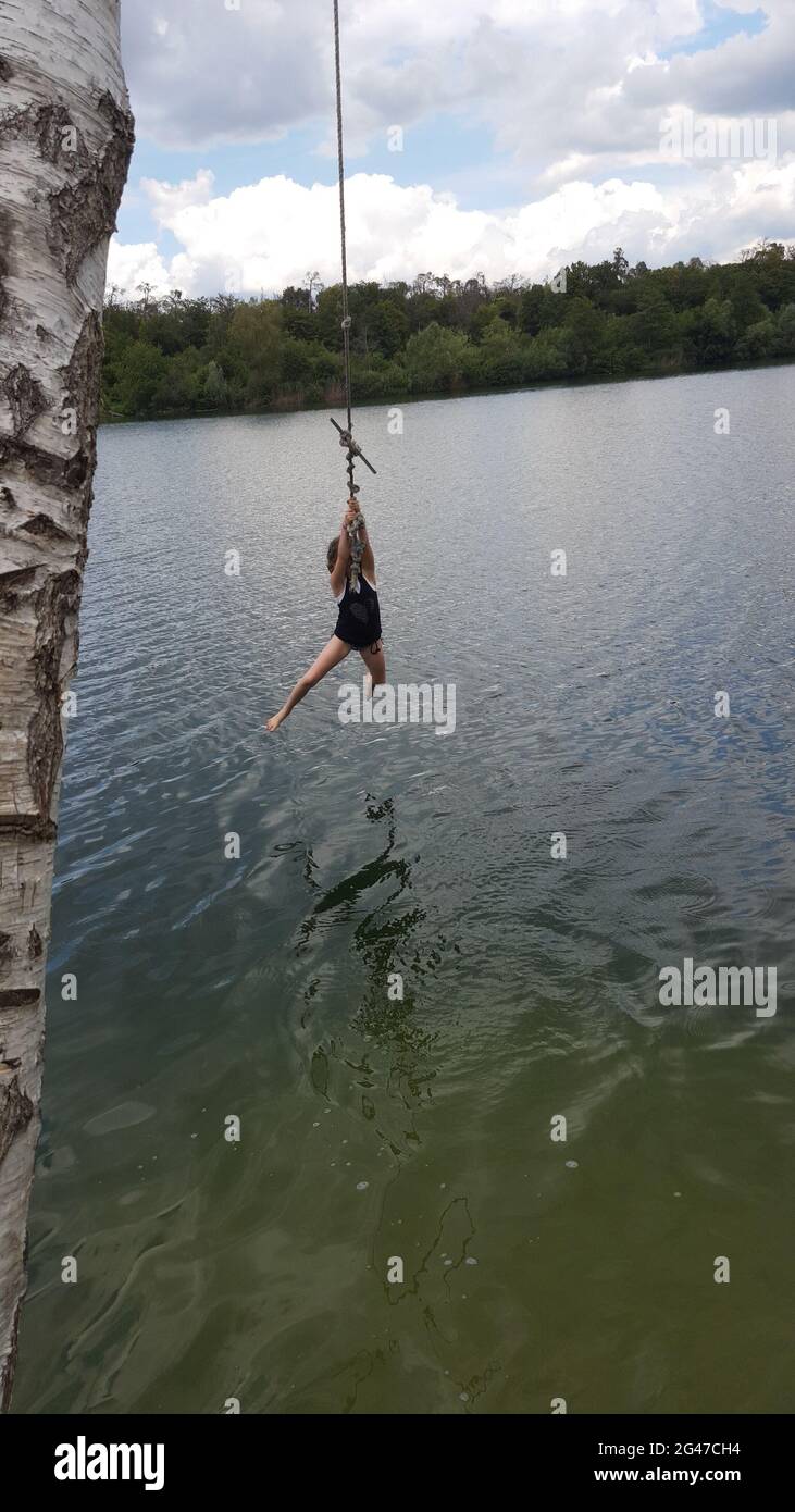 Cool shot of a female jumping into the lake with a rope hanging on the ...