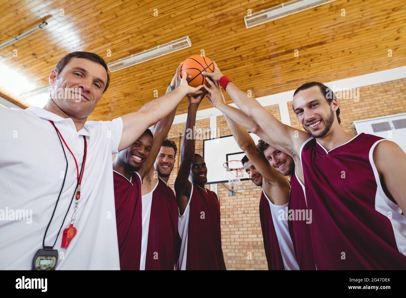 Players and coach holding basketball together in the court Stock Photo ...