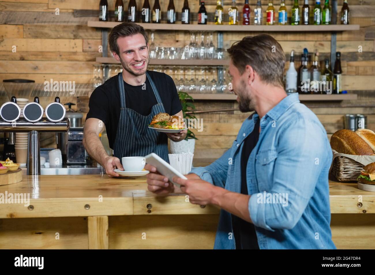 Waiter serving coffee to male customer at counter Stock Photo - Alamy