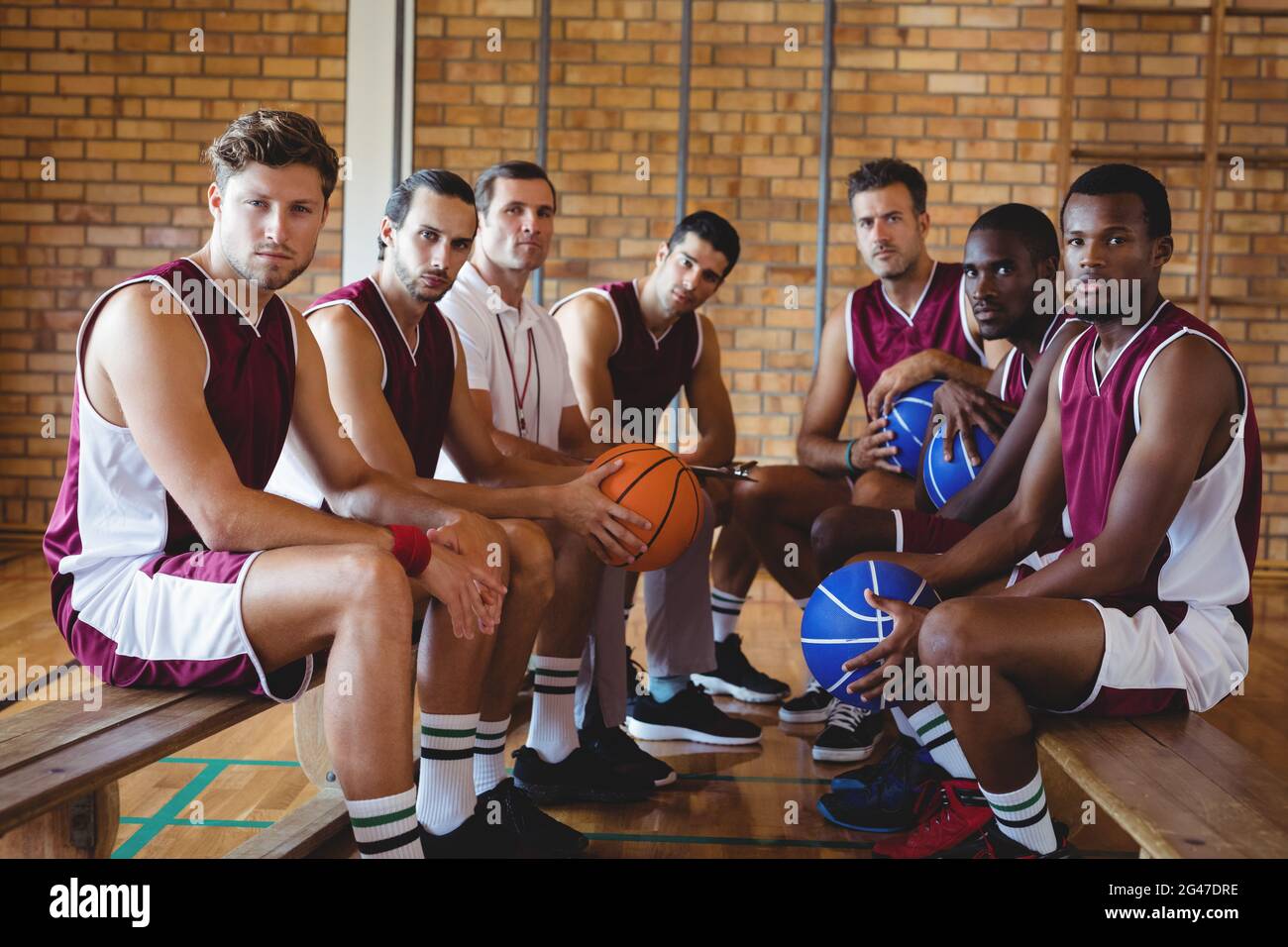 Confident coach and basketball player sitting on bench Stock Photo - Alamy