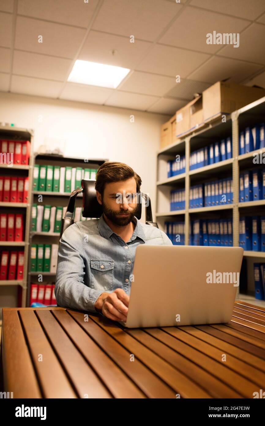 Business executive using laptop in file storage room Stock Photo - Alamy