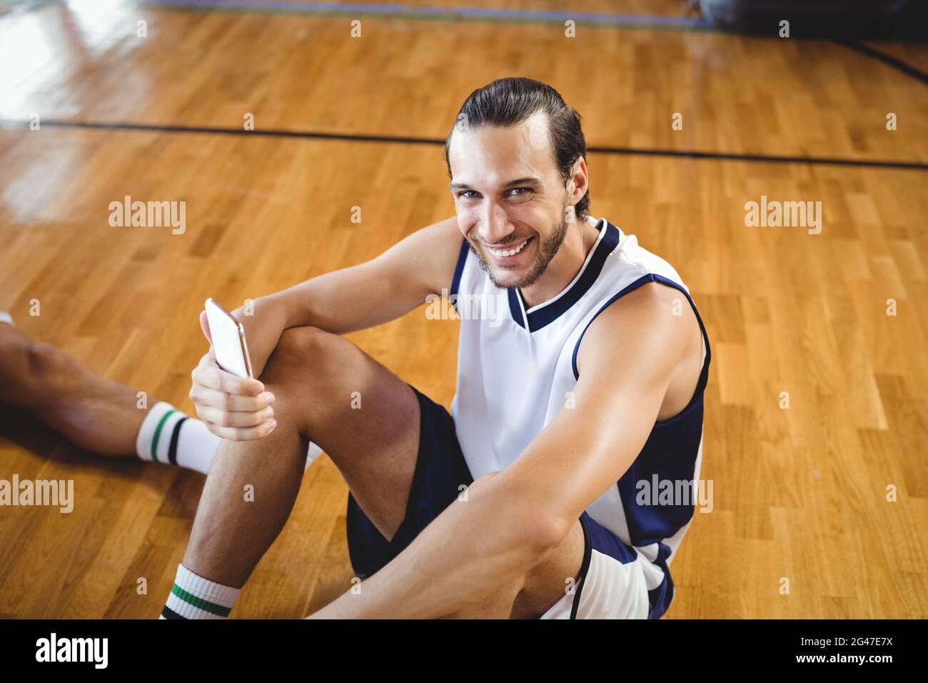 Portrait of smiling basketball player using mobile while relaxing Stock ...