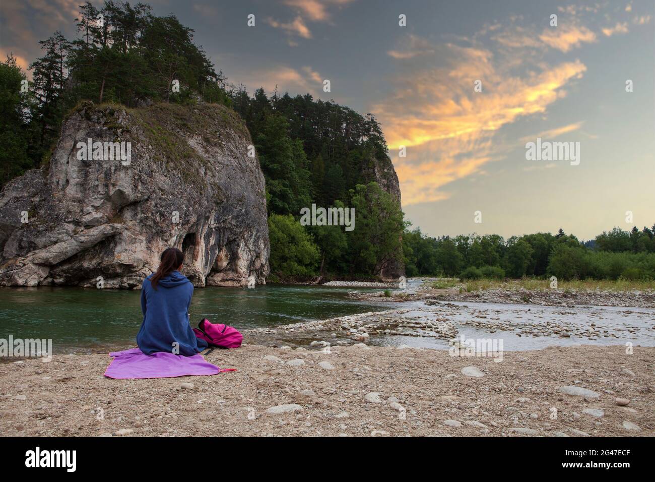 Woman hiking taking a break by a stream. A tourist with a backpack by ...