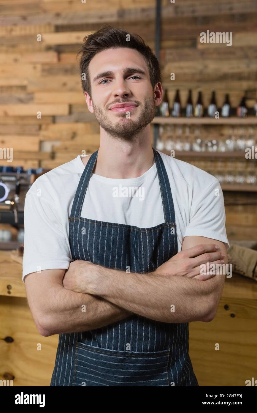 Portrait of smiling waiter standing with arms crossed Stock Photo - Alamy