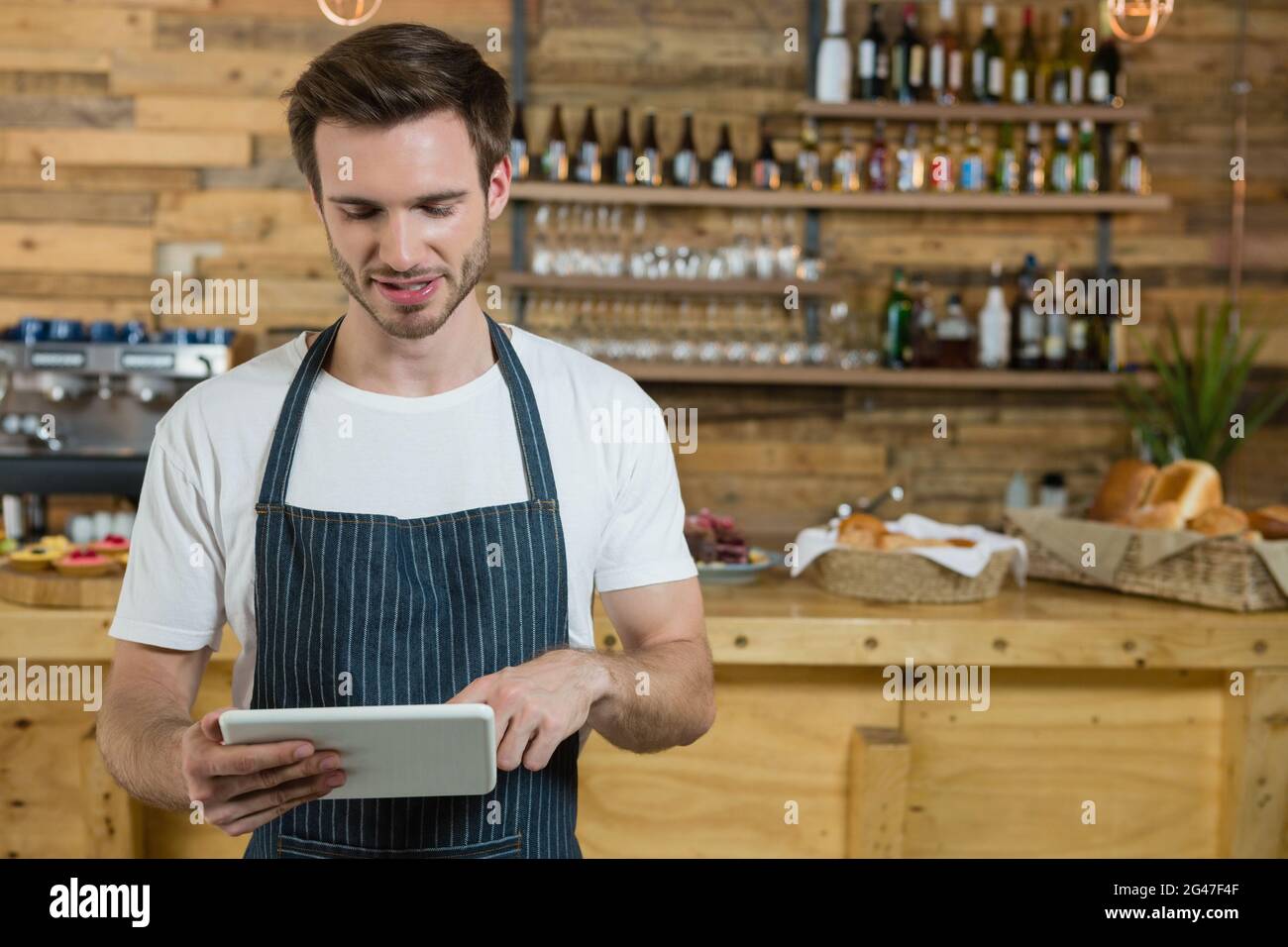 Waiter using digital tablet at counter Stock Photo - Alamy