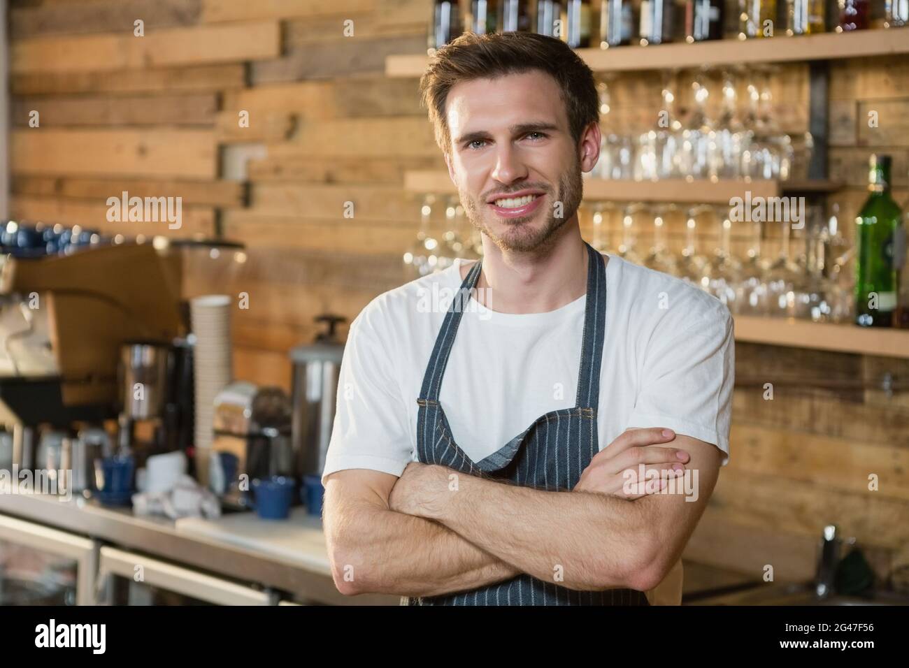 Portrait of smiling waiter standing with arms crossed at counter Stock ...